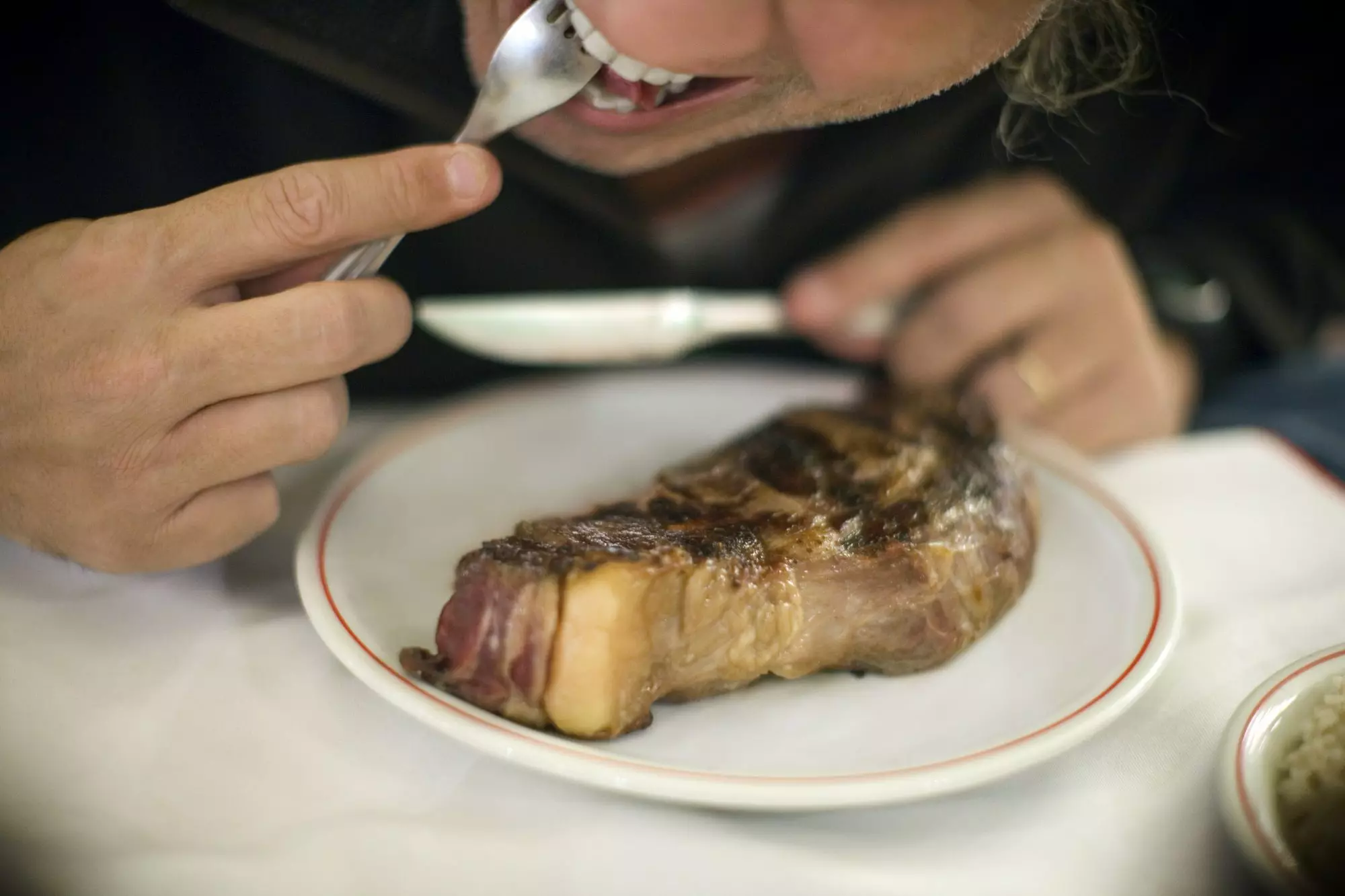 Man eating Bife de Chorizo steak yn Buenos Aires