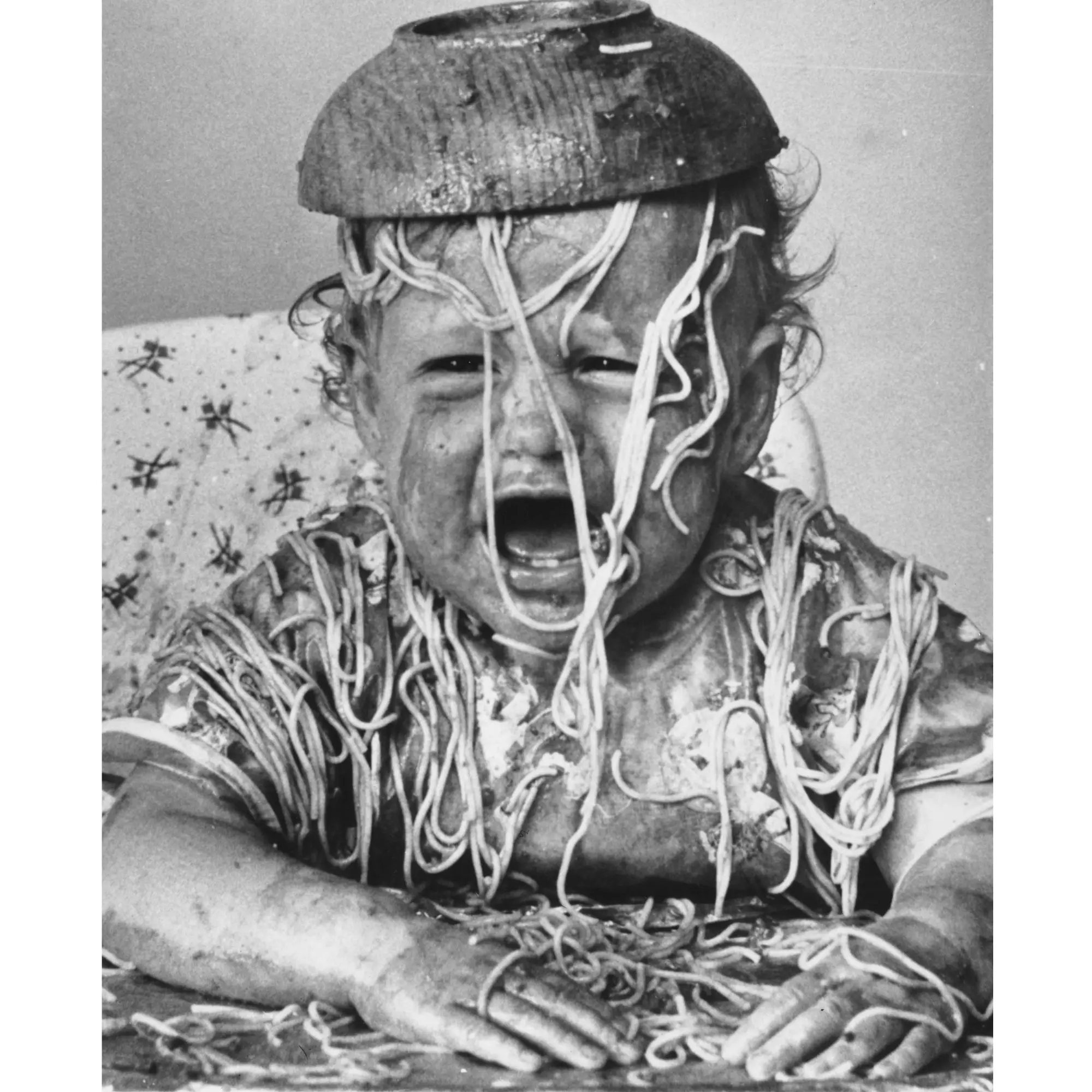 Ein Kind mit einer Schüssel Spaghetti auf dem Kopf