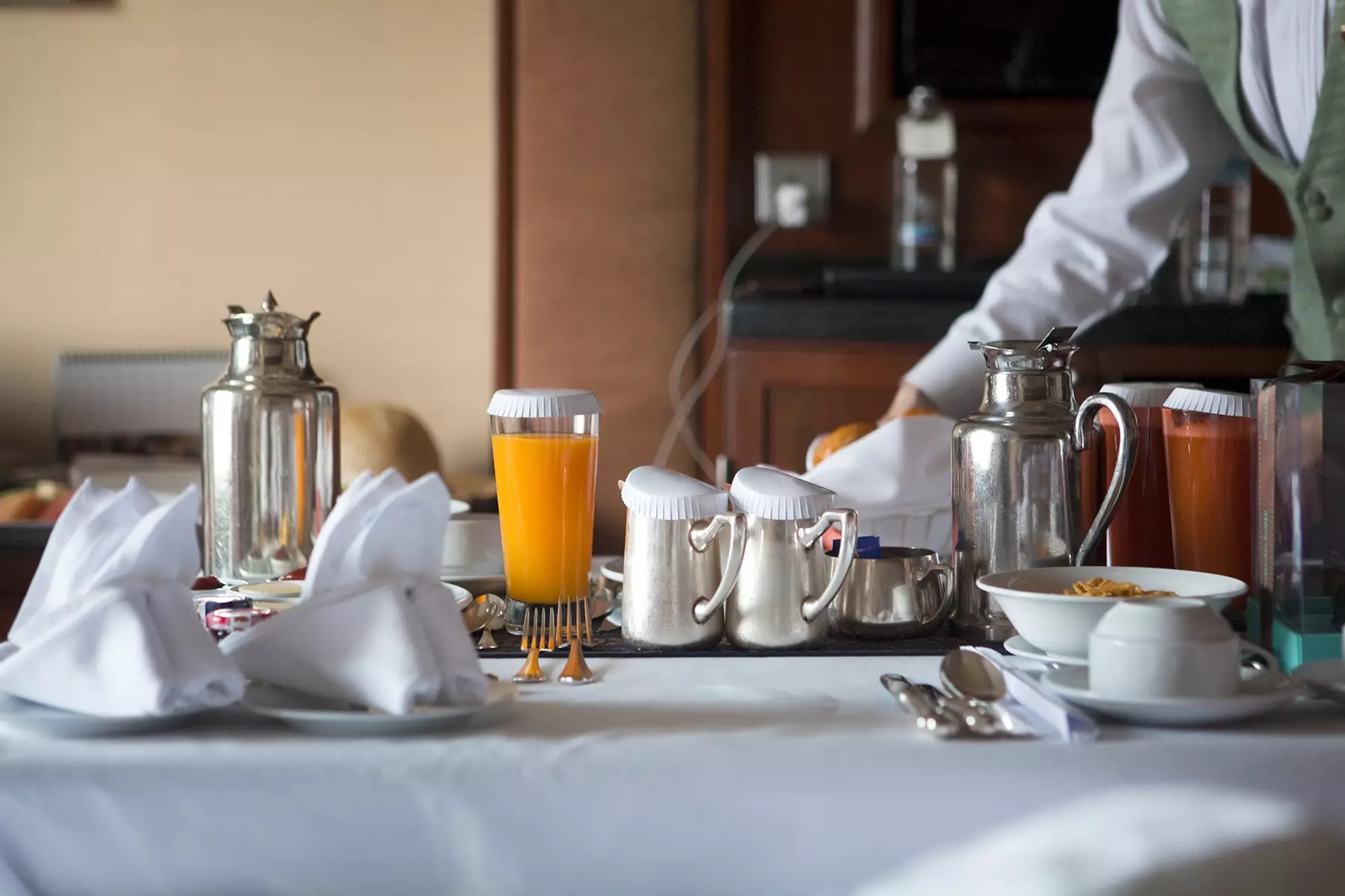 mesa de café da manhã em um quarto de hotel com frutas e sucos, café e chá