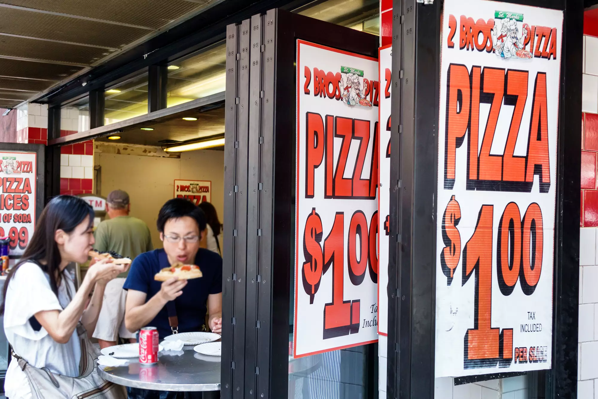 Un couple en train de manger une pizza au 2 Bros Pizza à New York