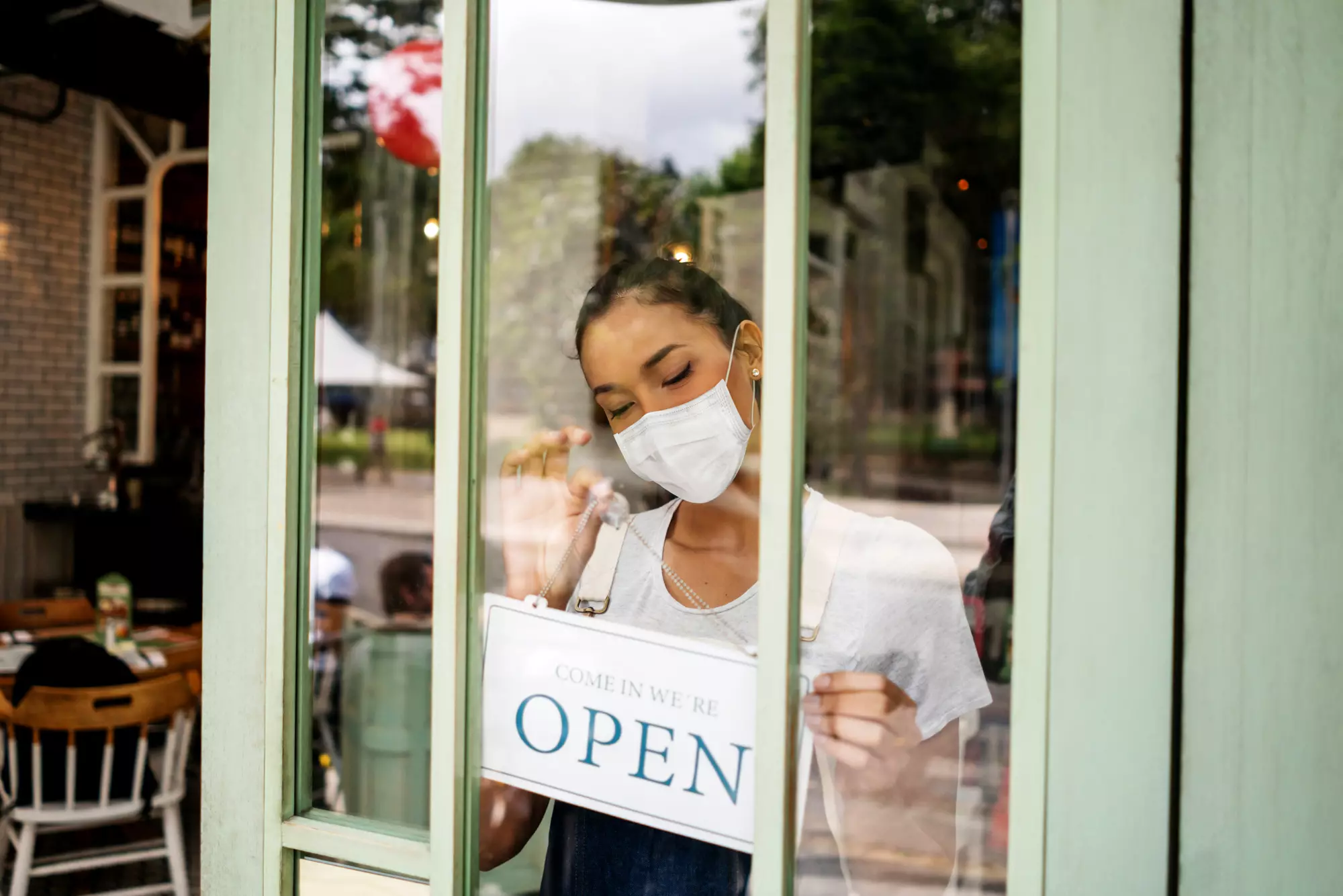 Restaurantangestellter hängen offenes Schild, das eine Maske trägt