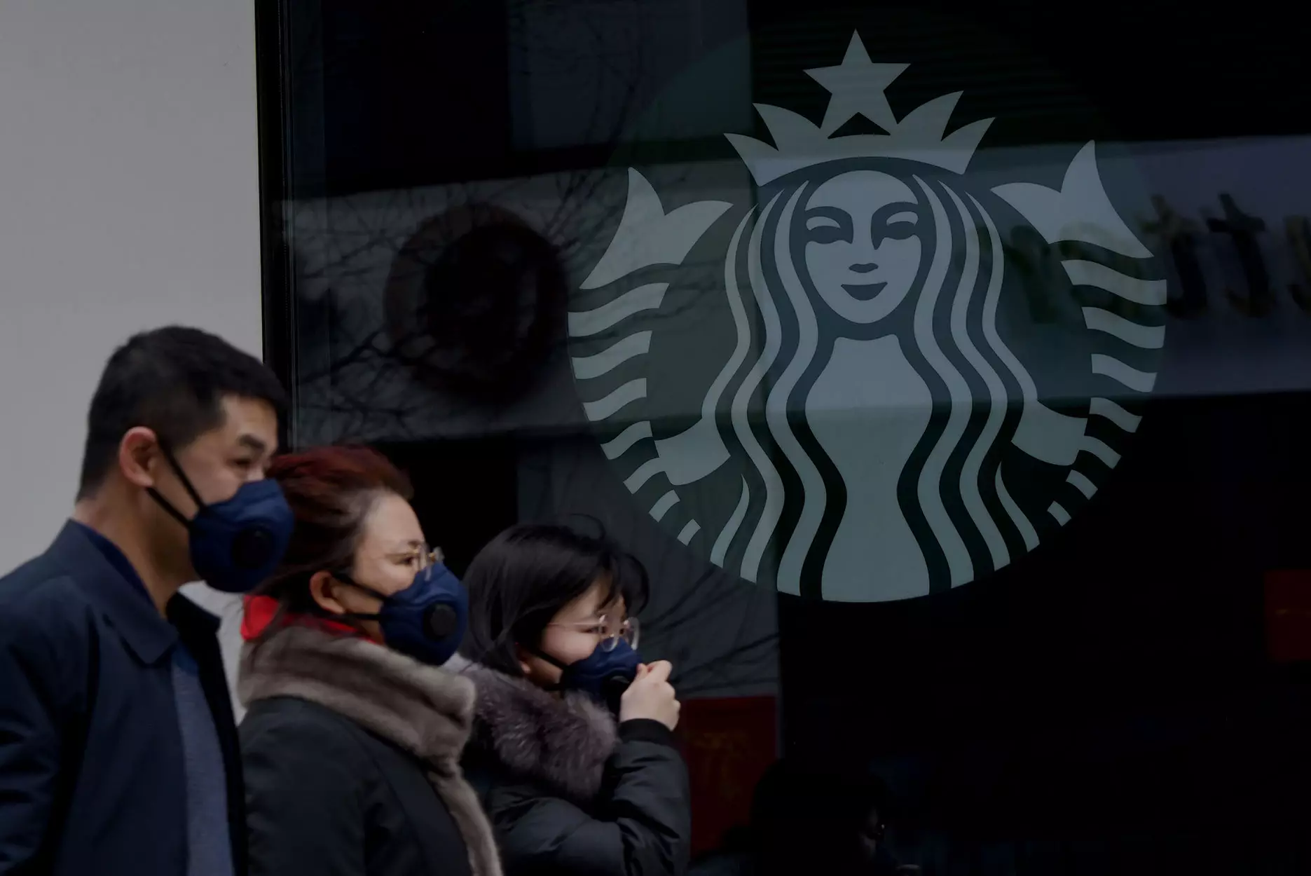 O tagata o loʻo ofuina matapulepule puipui i luma o se nofoaga Starbucks i Beijing