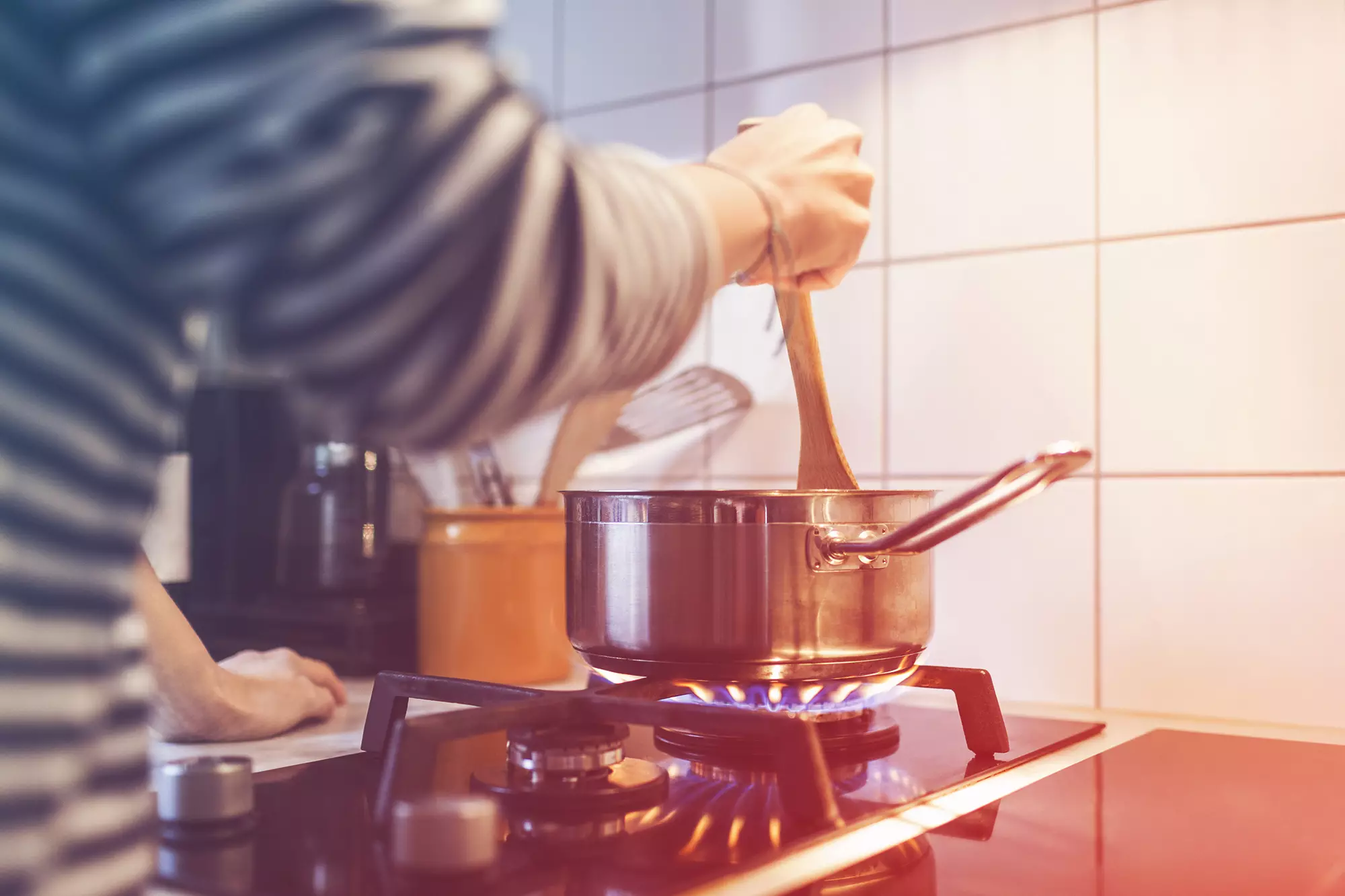 Обрізане зображення жінки, яка тримає лопатку в каструлі під час приготування їжі на плиті, приготування їжі-вбити-коронавірус, covid-19, коронавірус, приготування їжі