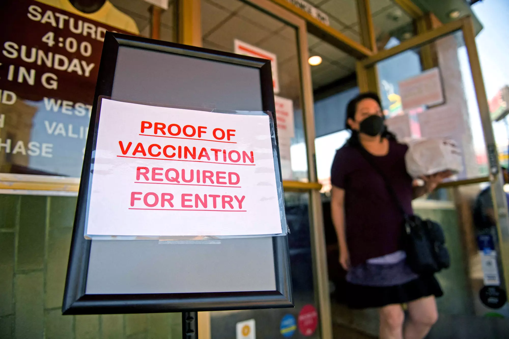 Έξω από το Langer's Deli στο Λος Άντζελες της Καλιφόρνια, στις 7 Αυγούστου 2021, εμφανίζεται μια πινακίδα που δηλώνει ότι απαιτείται εμβολιασμός για τον Covid-19