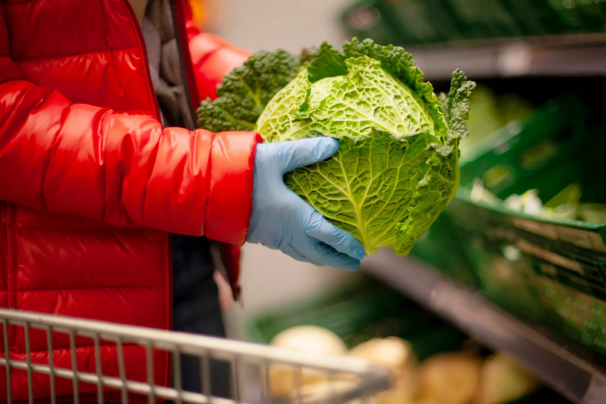 Особа држи зелену салату у пролазу за производе